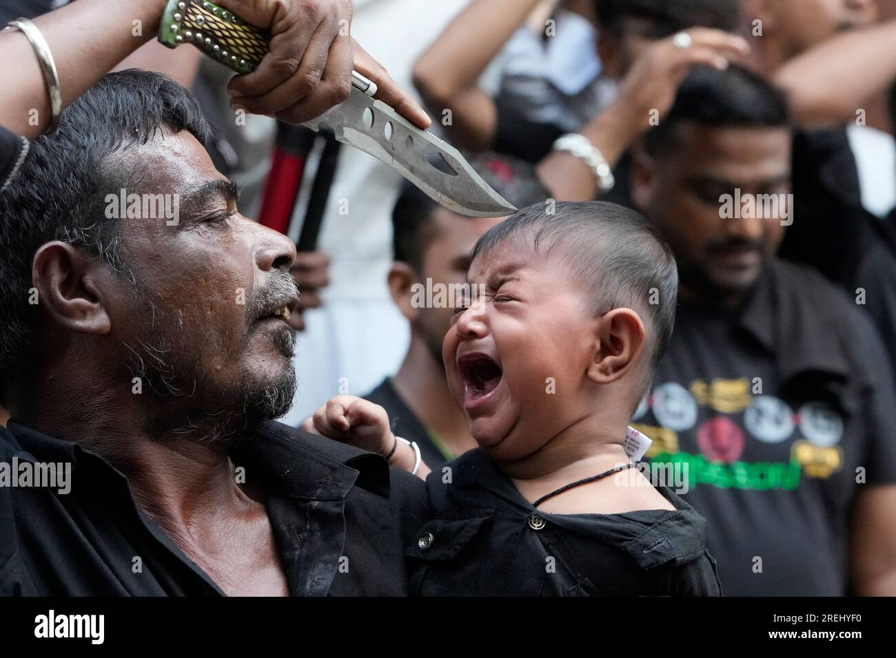 A Shiite Muslim touches the forehead of a child with the point of his knife during a Muharram ...