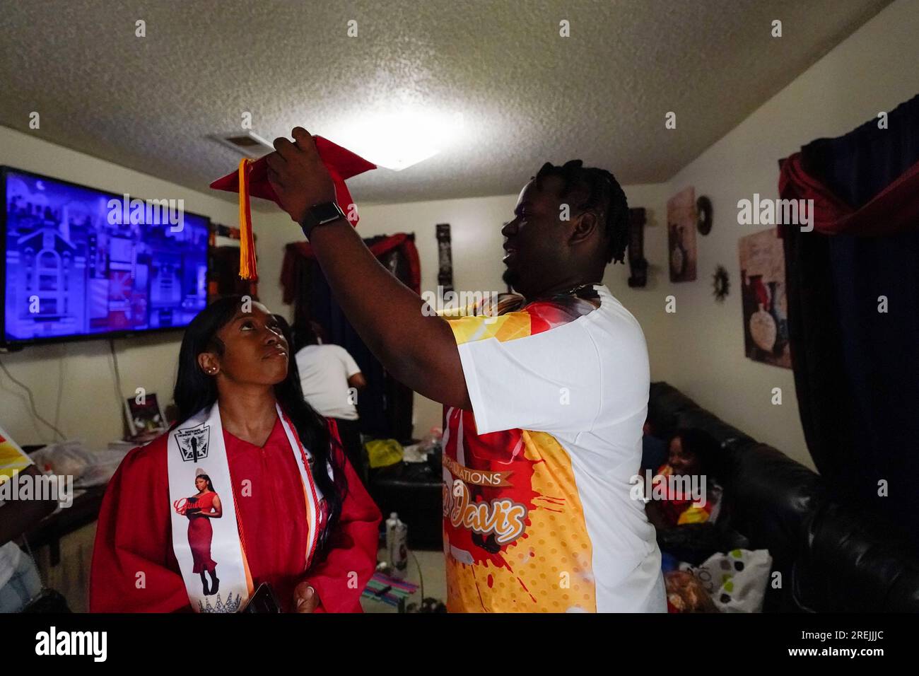 Jajuan McGee puts a graduation cap on his cousin, Kaylyn Davis, whose ...