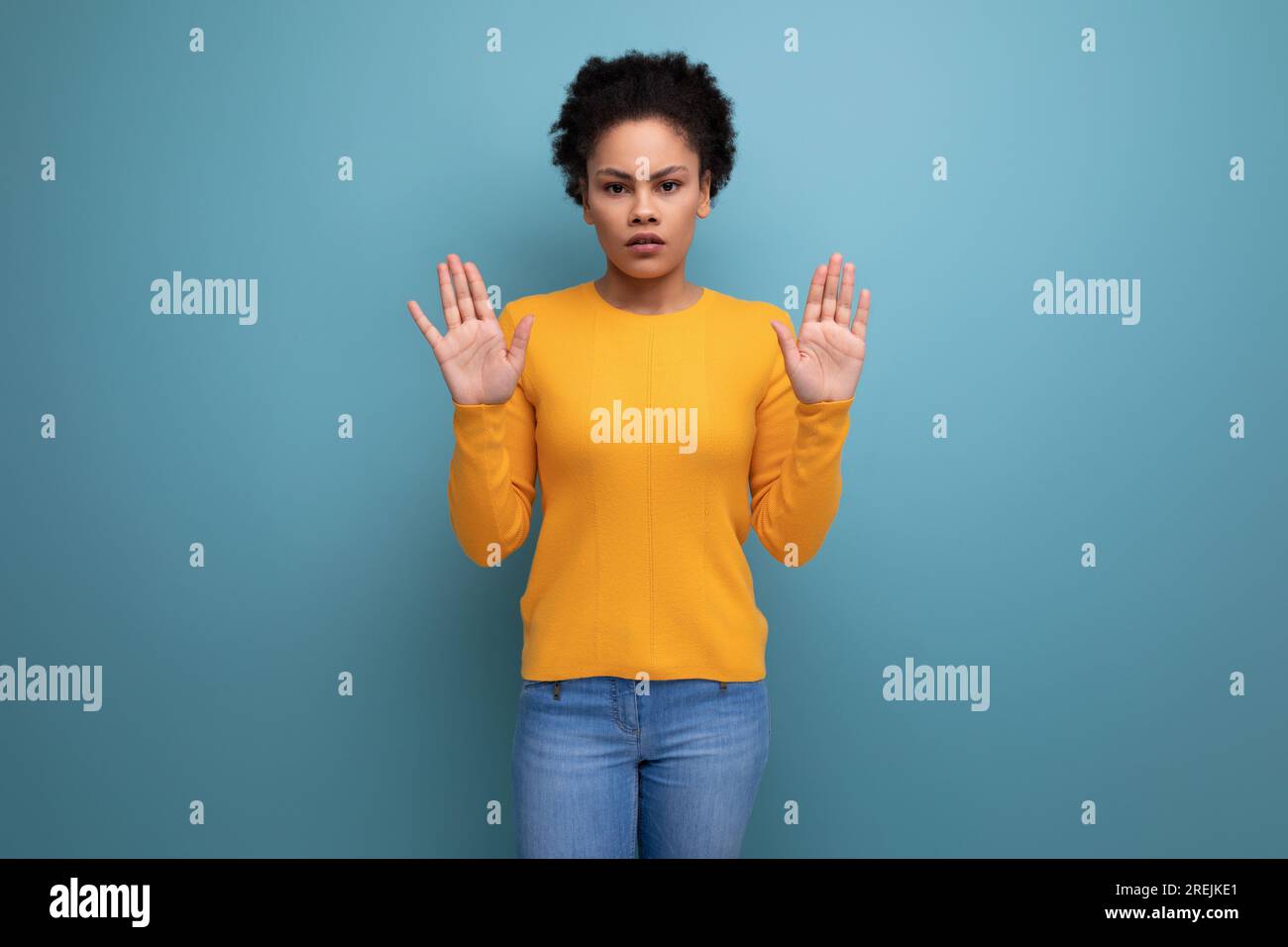 surprised young latin woman with afro hair raised her hands up showing ...
