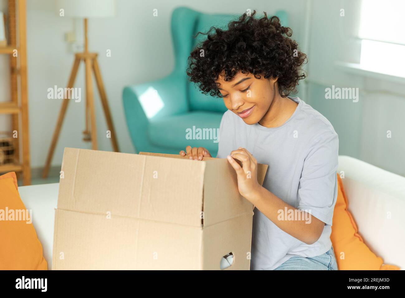 African girl unpacking delivery looking in box. Happy woman opening ...