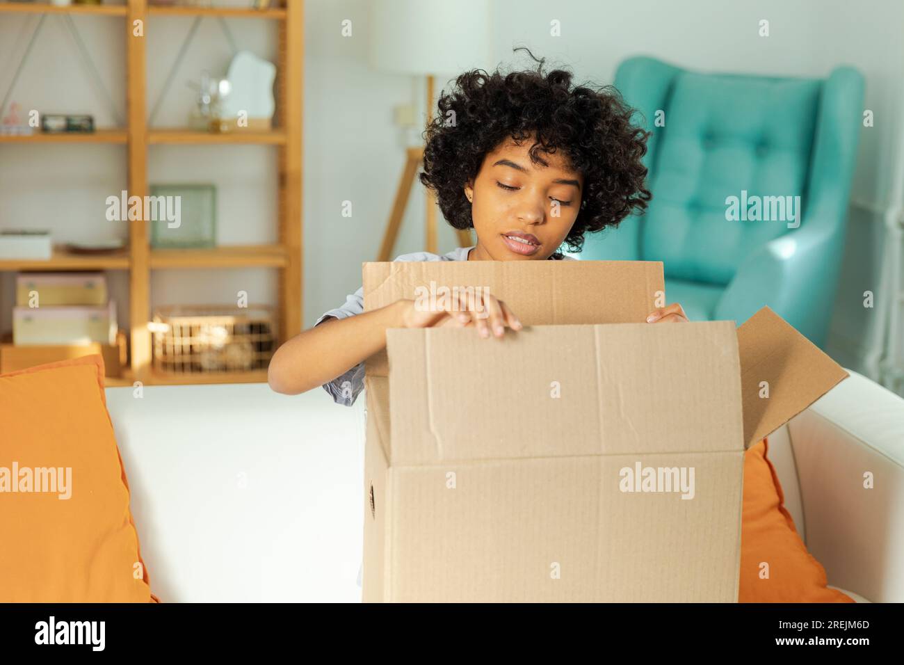 African girl unpacking delivery looking in box. Happy woman opening ...