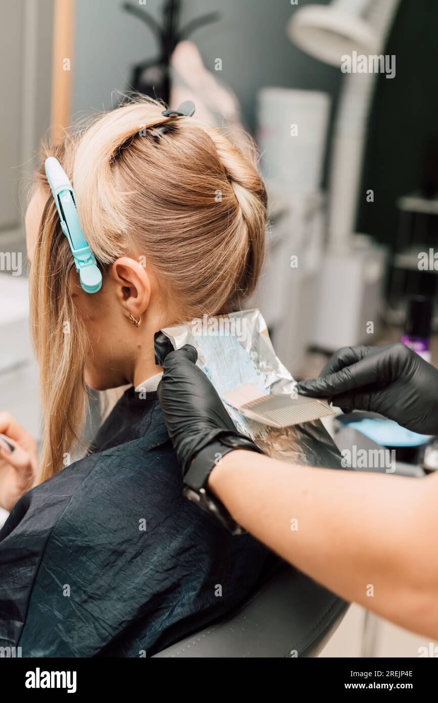 Hair coloring in white in a beauty salon. Process of applying dye to ...