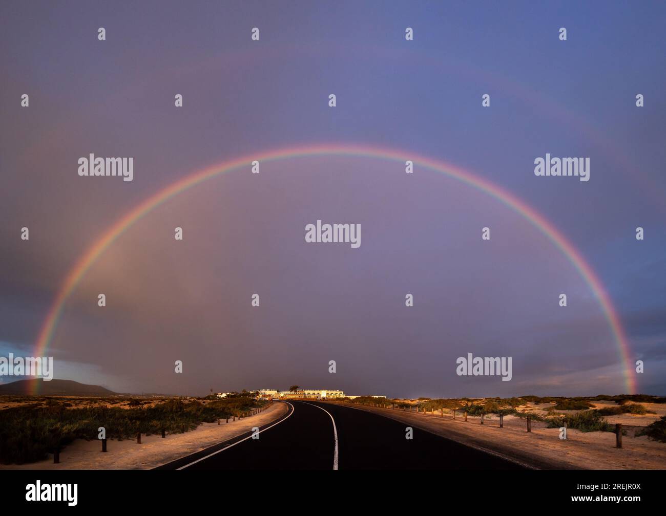 Rainbow over sand dunes and a dune road. Corralejo National Park in the ...