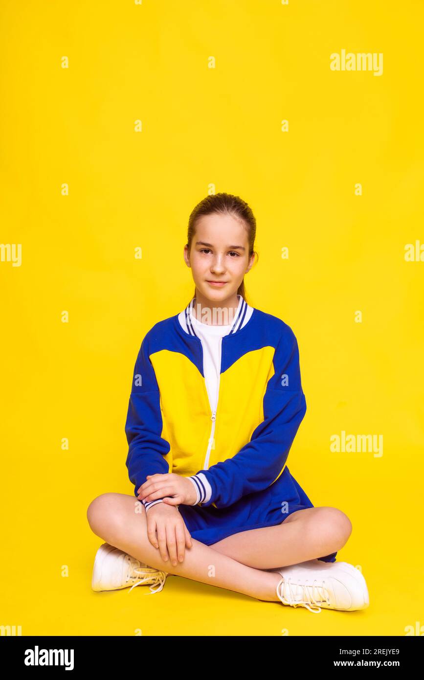 teen cheerleader girl in sports blue and yellow clothes sitting over ...