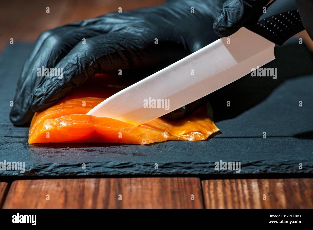 Closeup of chefs hands are slicing fresh fish slice. Chef is cutting ...