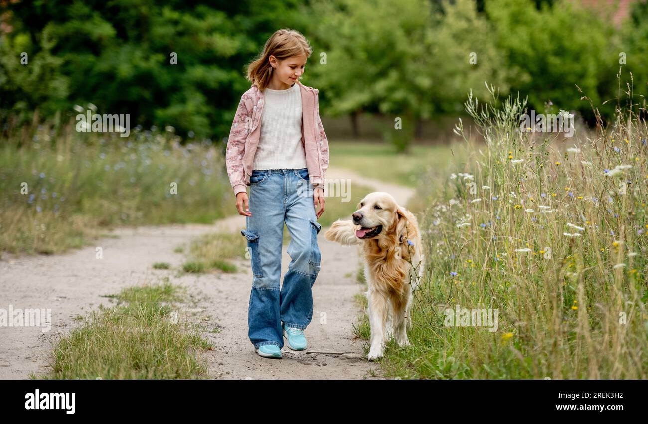 Preteen girl with golden retriever dog walking at nature. Cute child ...