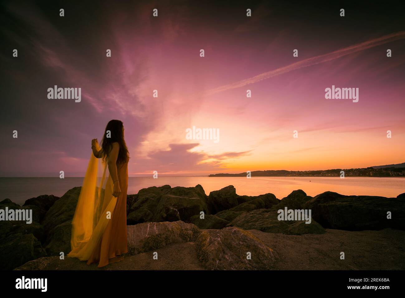 woman in a yellow dress and cape observing a magnificent sunrise on the ...