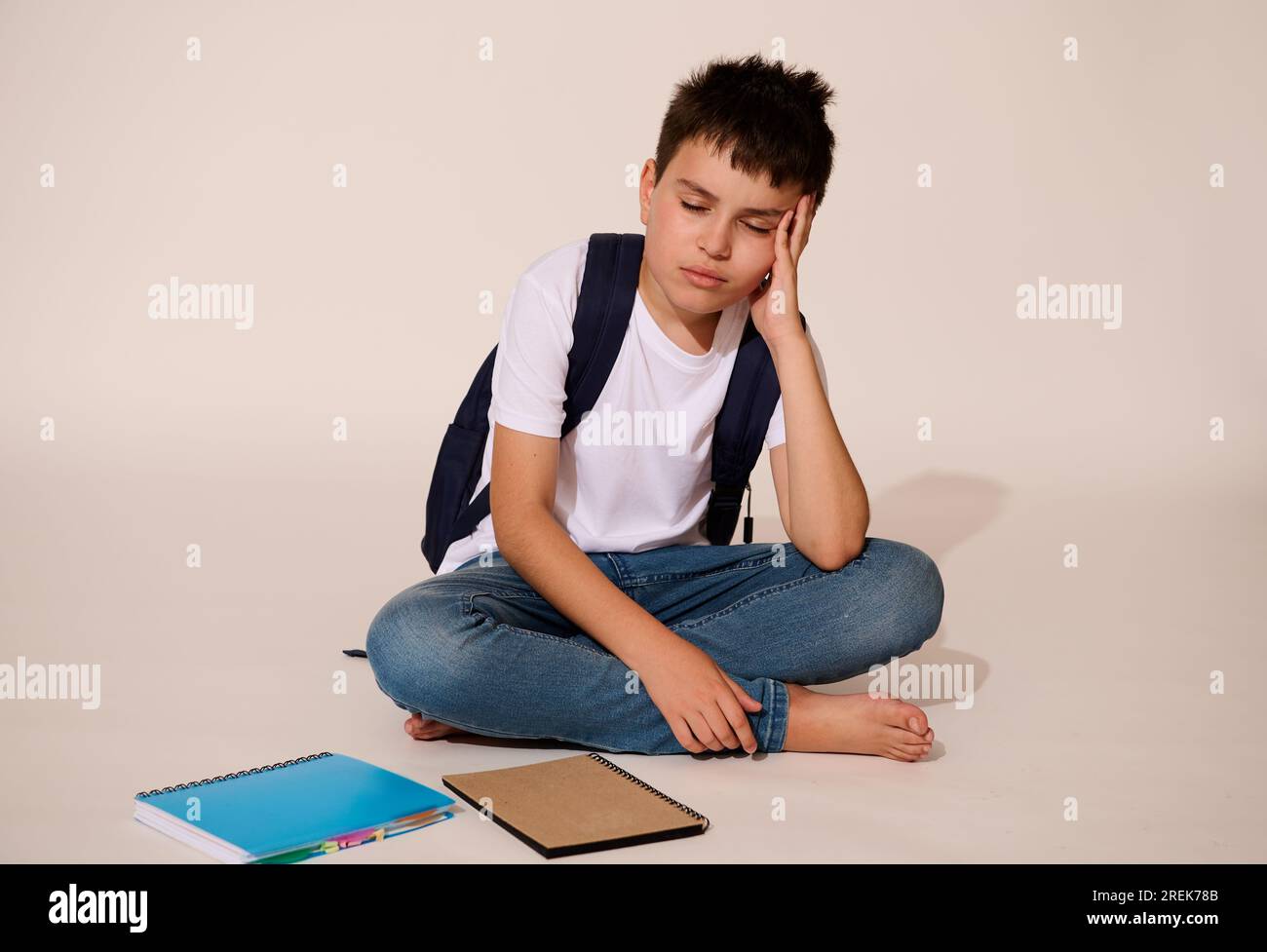 Studio portrait of an upset teenager, a schoolboy holding his head ...