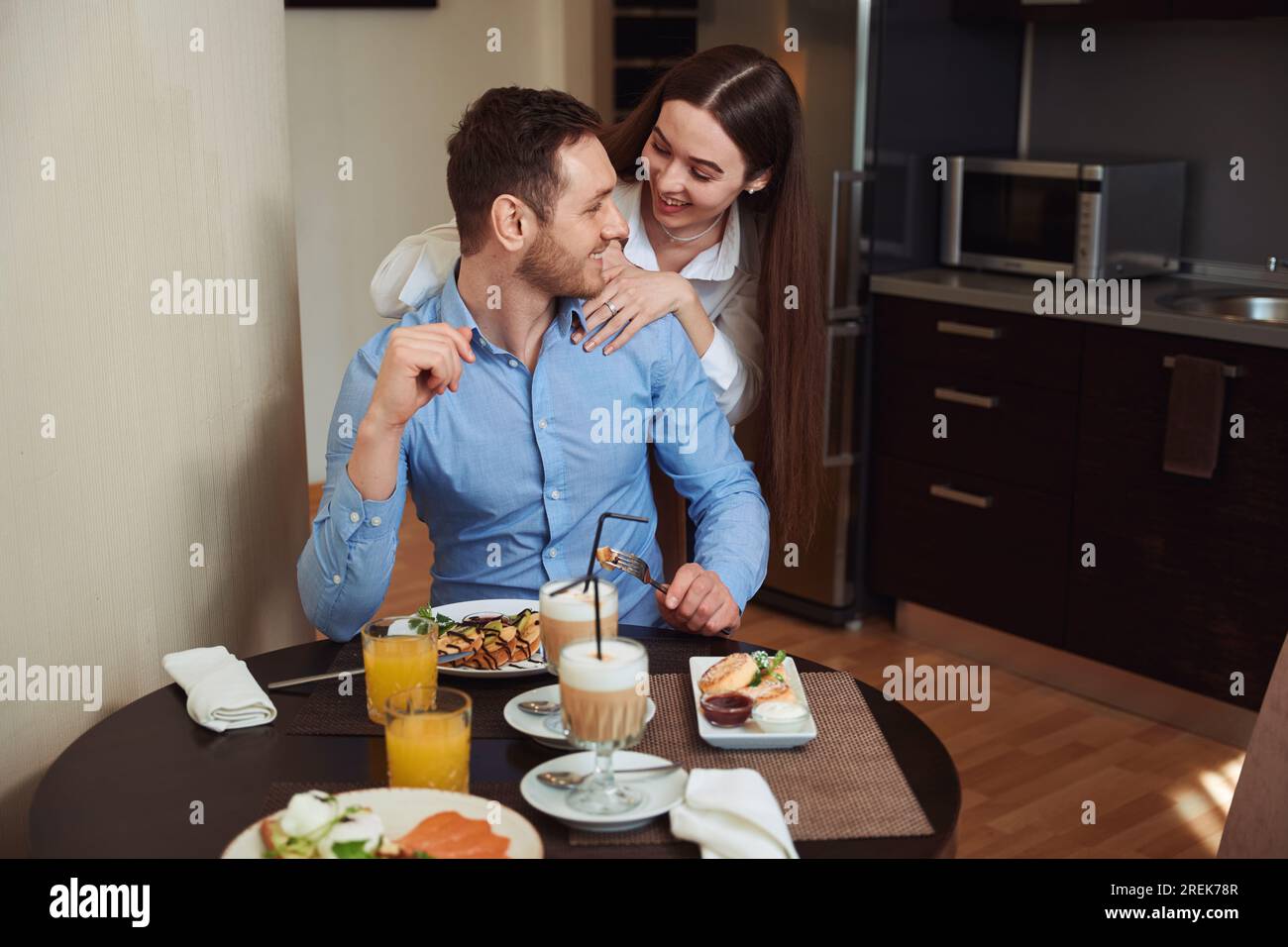 Happy woman hugging man in the kitchen Stock Photo - Alamy
