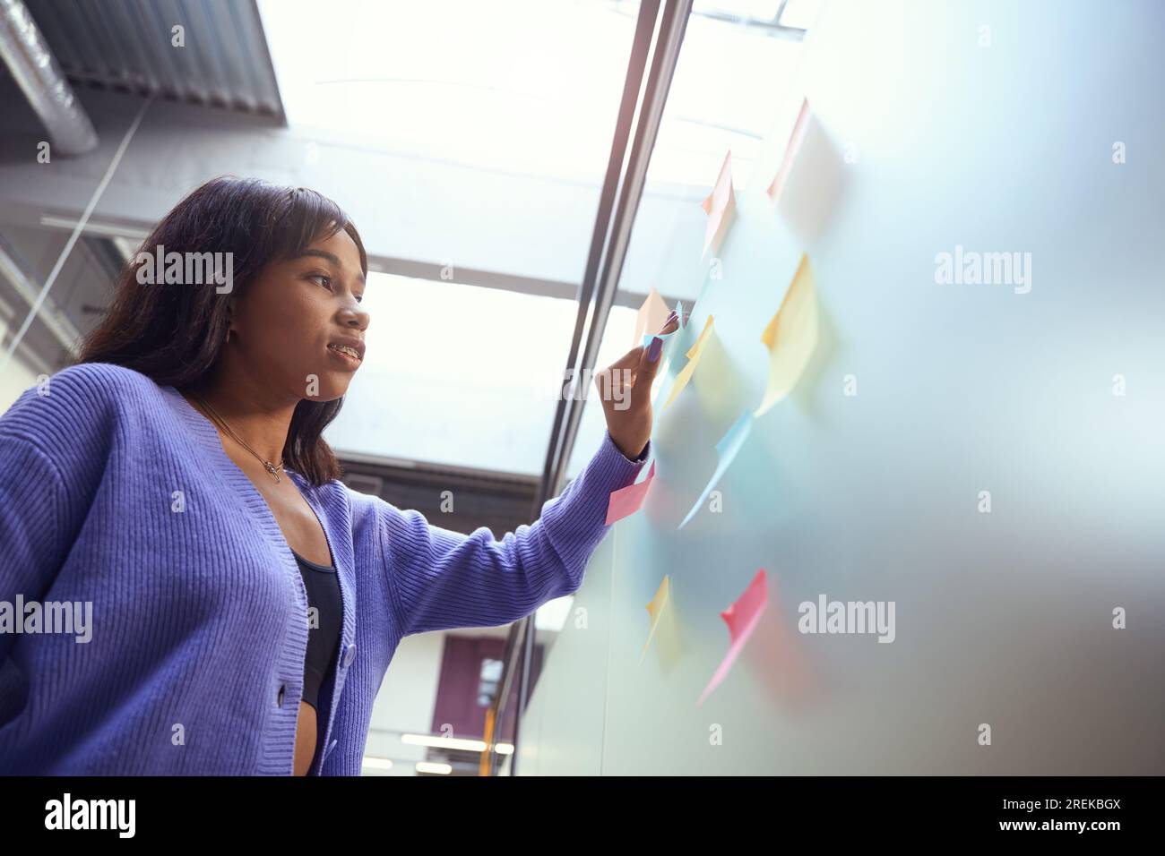 Pretty woman sticking sticky notes in modern room Stock Photo - Alamy