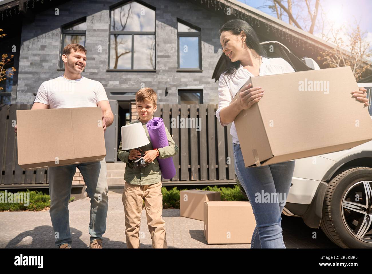 Family happily brings the boxes into their new home Stock Photo - Alamy