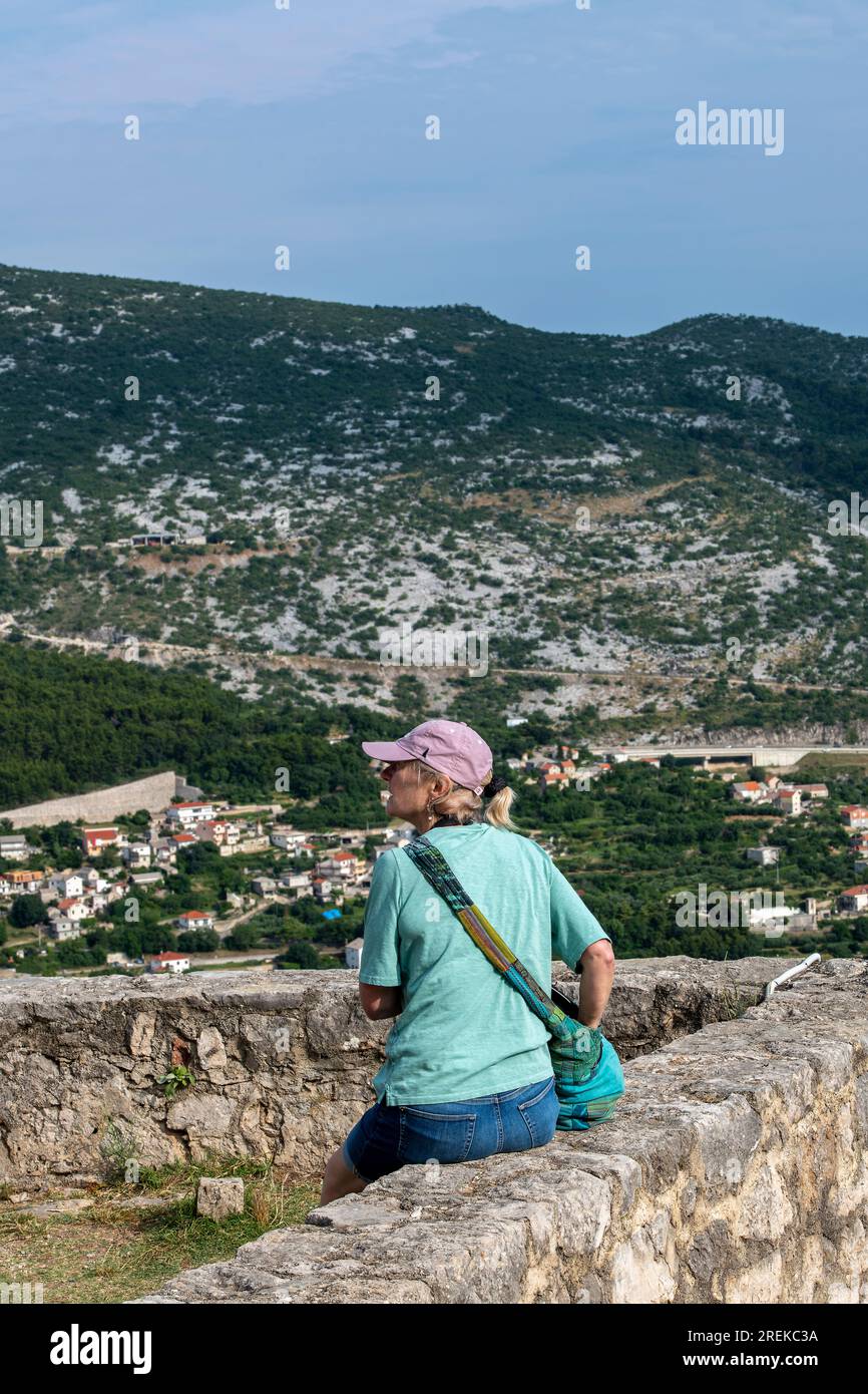 woman sitting on castle wall while visiting klis castle on the ...