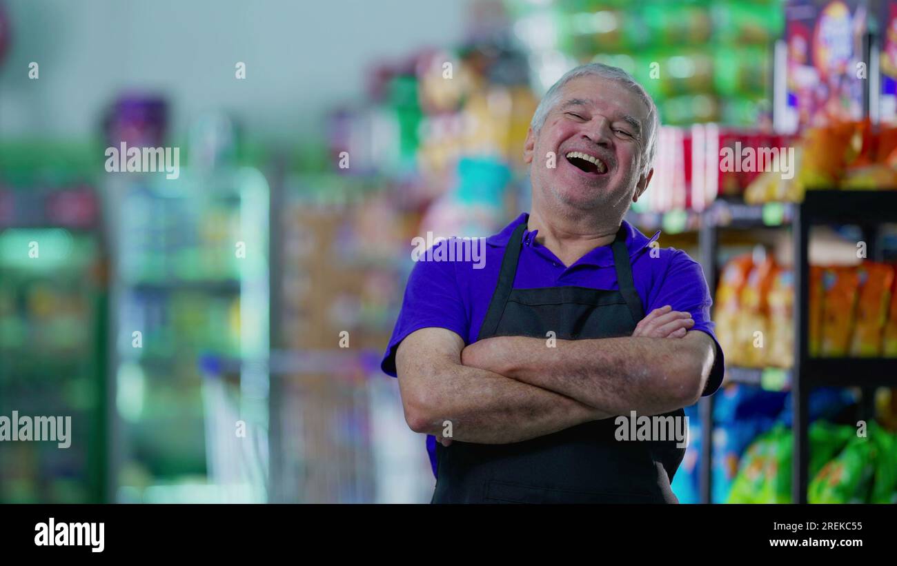 Happy older worker staff laughing and smiling inside supermarket ...