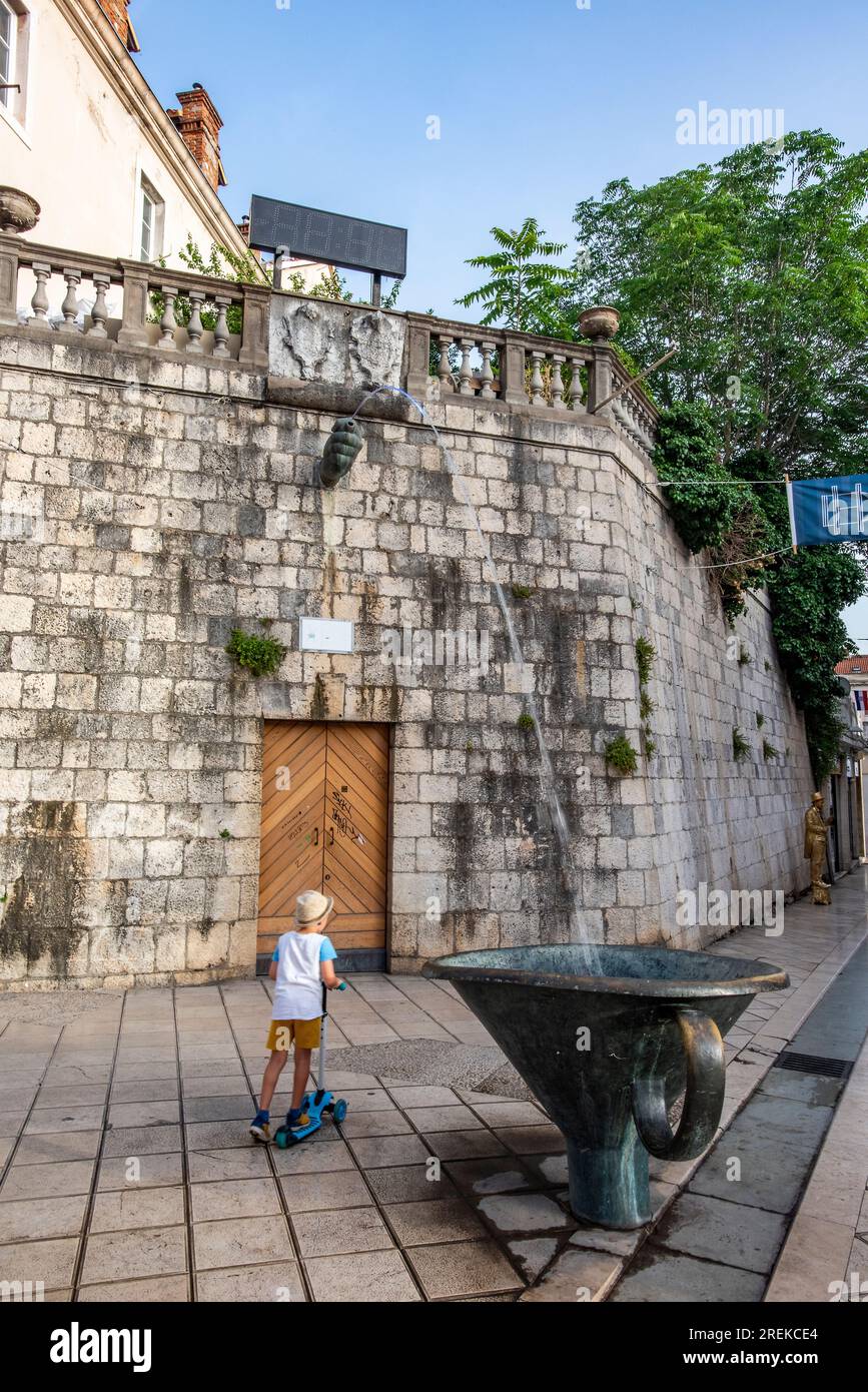 young boy watching a water fountain in the old town of grad split in ...