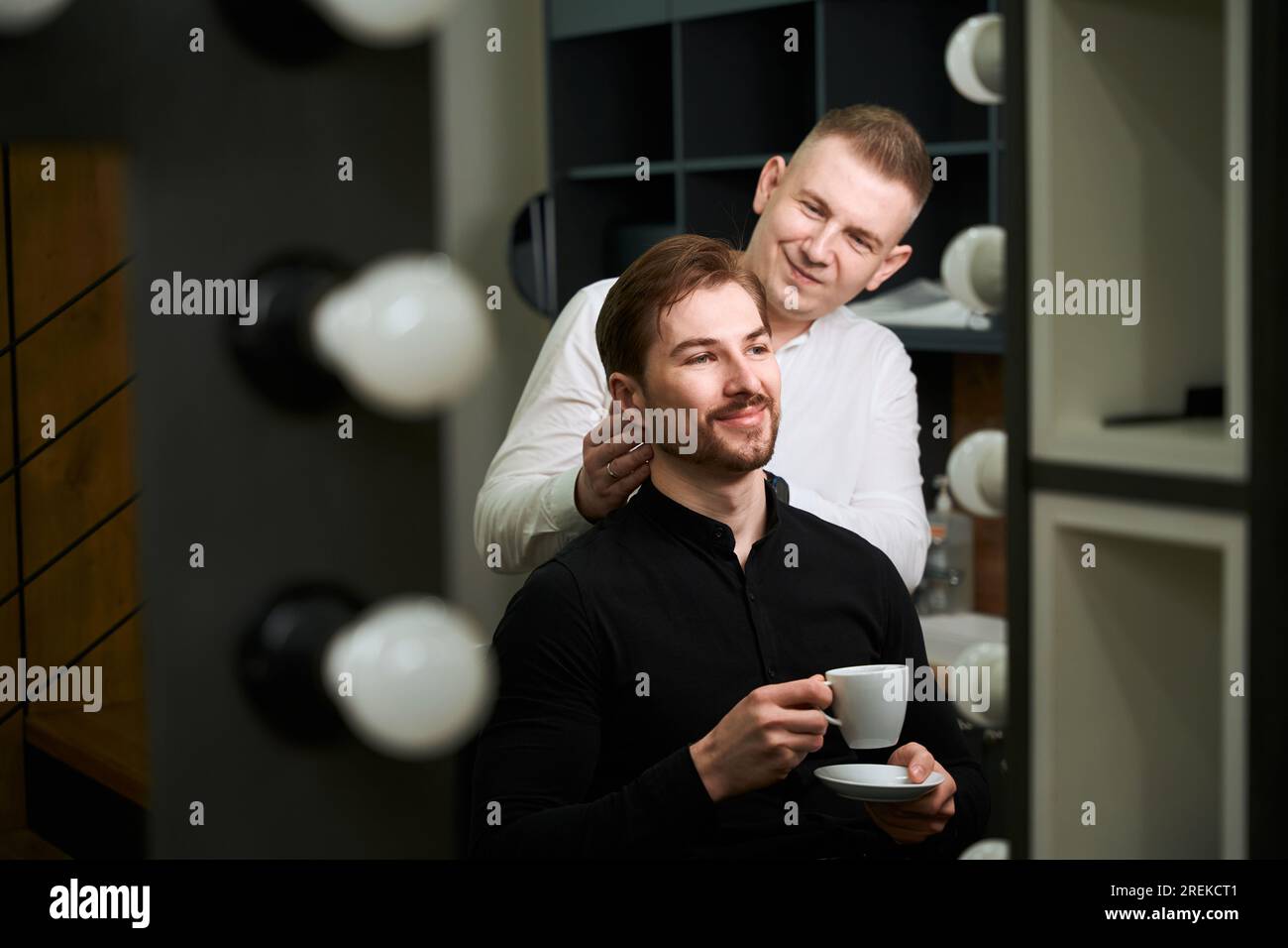 Smiling client getting served by barber in hair salon Stock Photo - Alamy