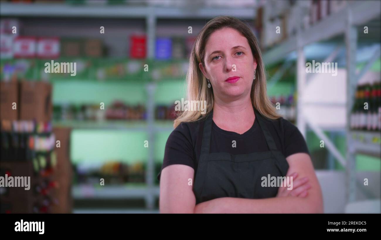 Female staff of Supermarket standing in aisle next to product inventory ...