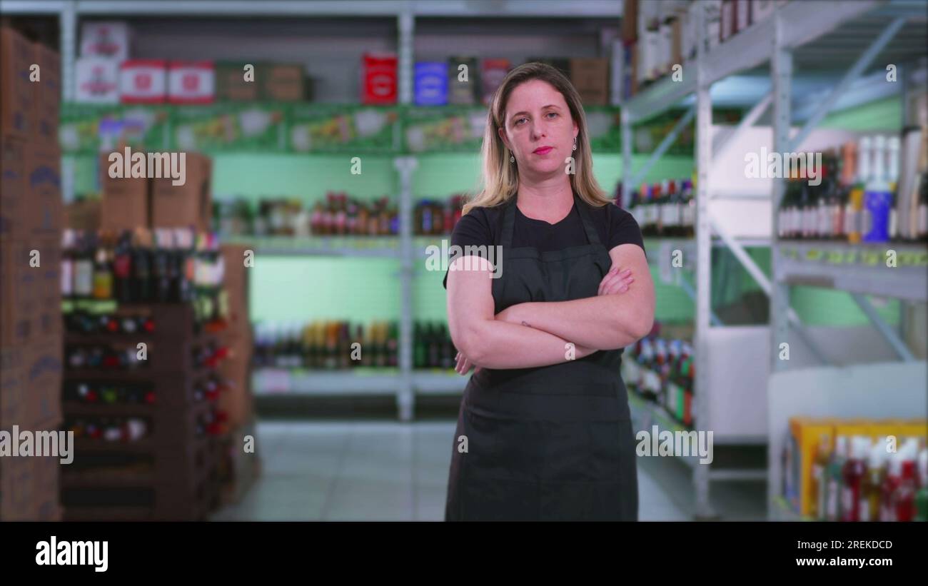Female staff of Supermarket standing in aisle next to product inventory ...