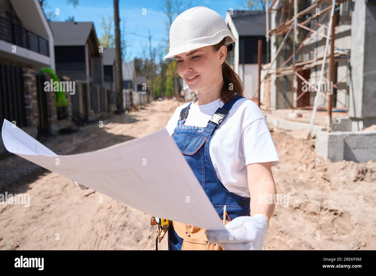 Woman civil engineer in hardhat and overall looking through buildings ...