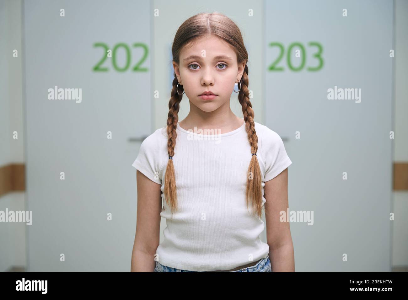 Sad child with pigtails stands in a bright hospital corridor Stock ...