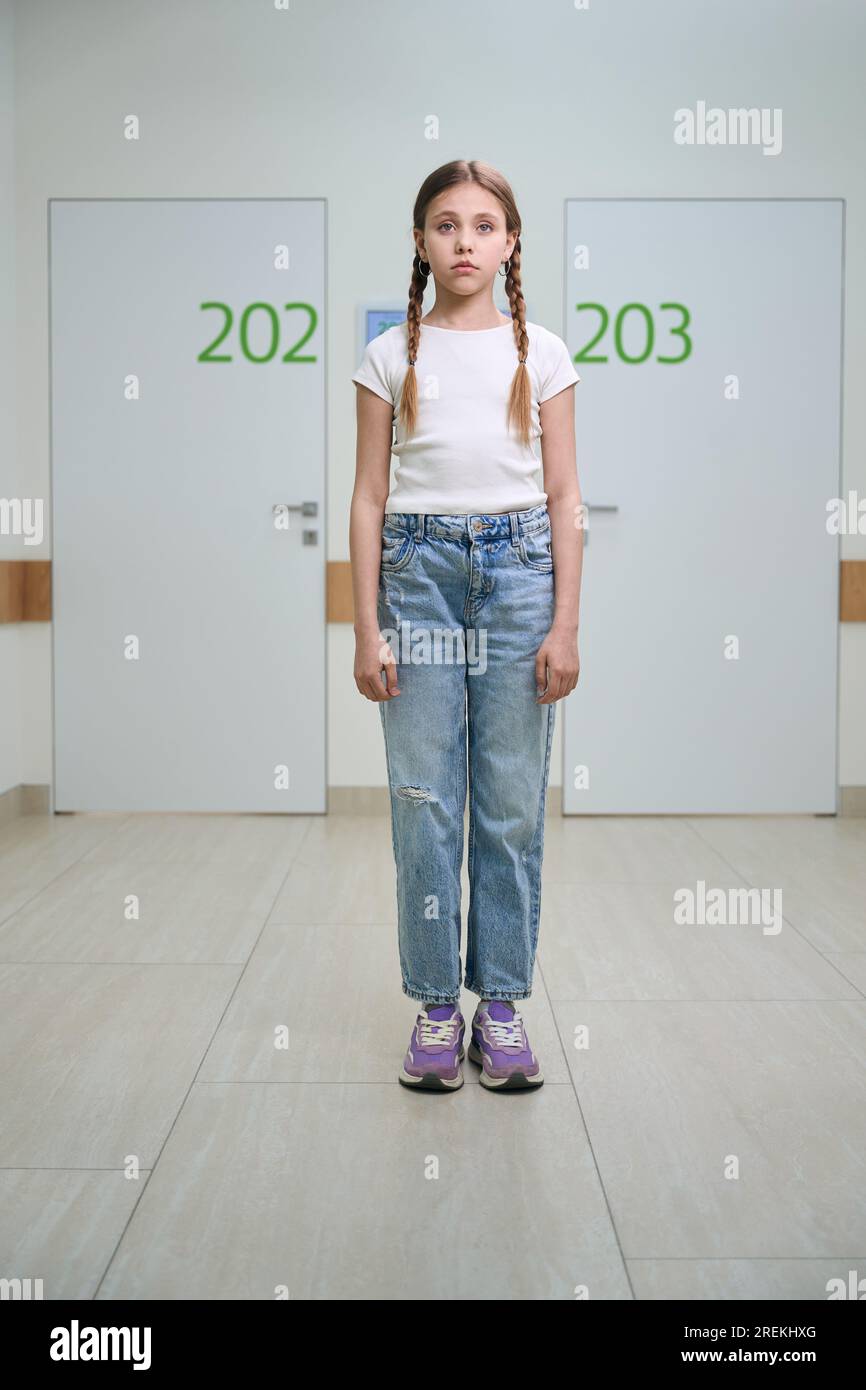 Sad girl with pigtails stands in a bright hospital corridor Stock Photo ...