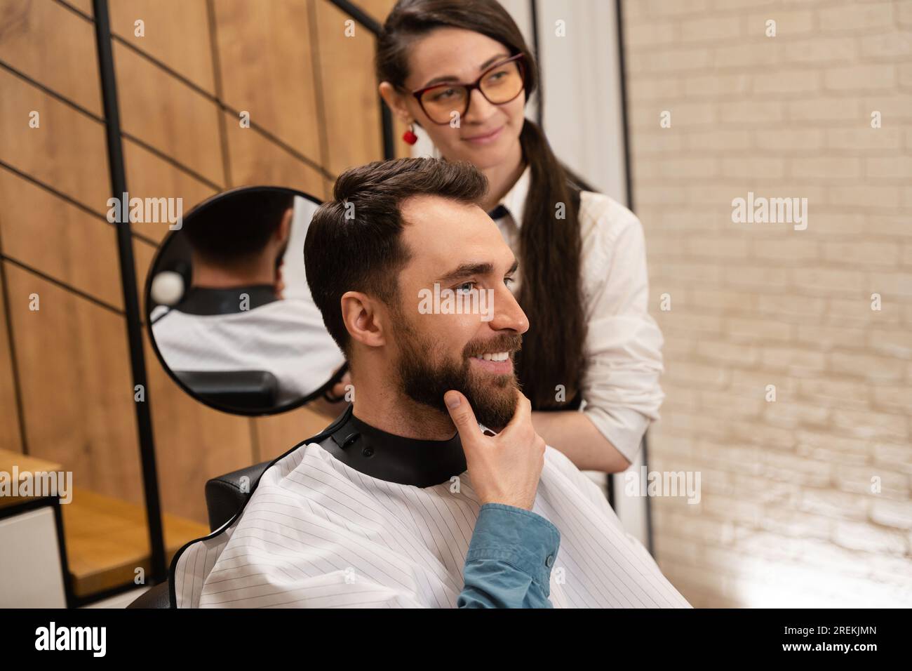 Female barber demonstrates his hairstyle to the client in mirror Stock ...