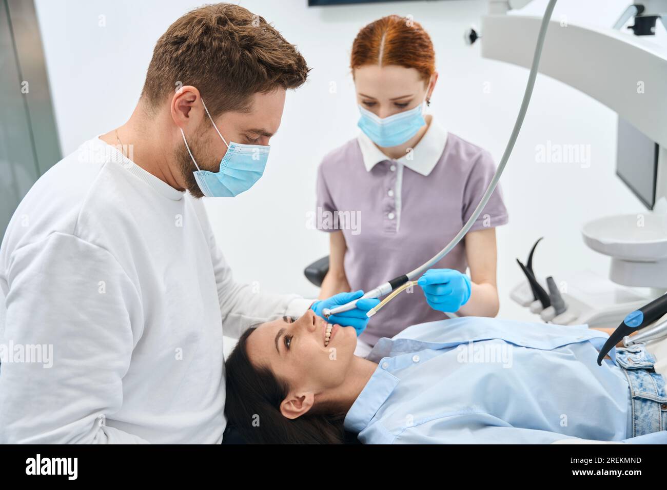 Professional dentist in uniform talking to female client during teeth ...