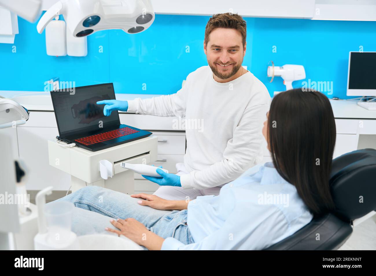 Smiling dentist showing image of client teeth on digital display Stock ...