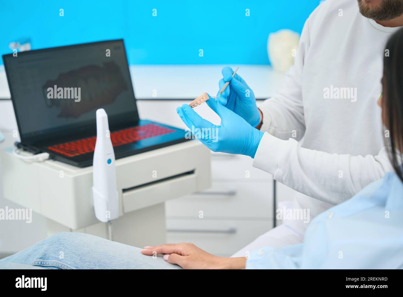 Male orthodontist using teeth prosthesis and sickle probe to show ...