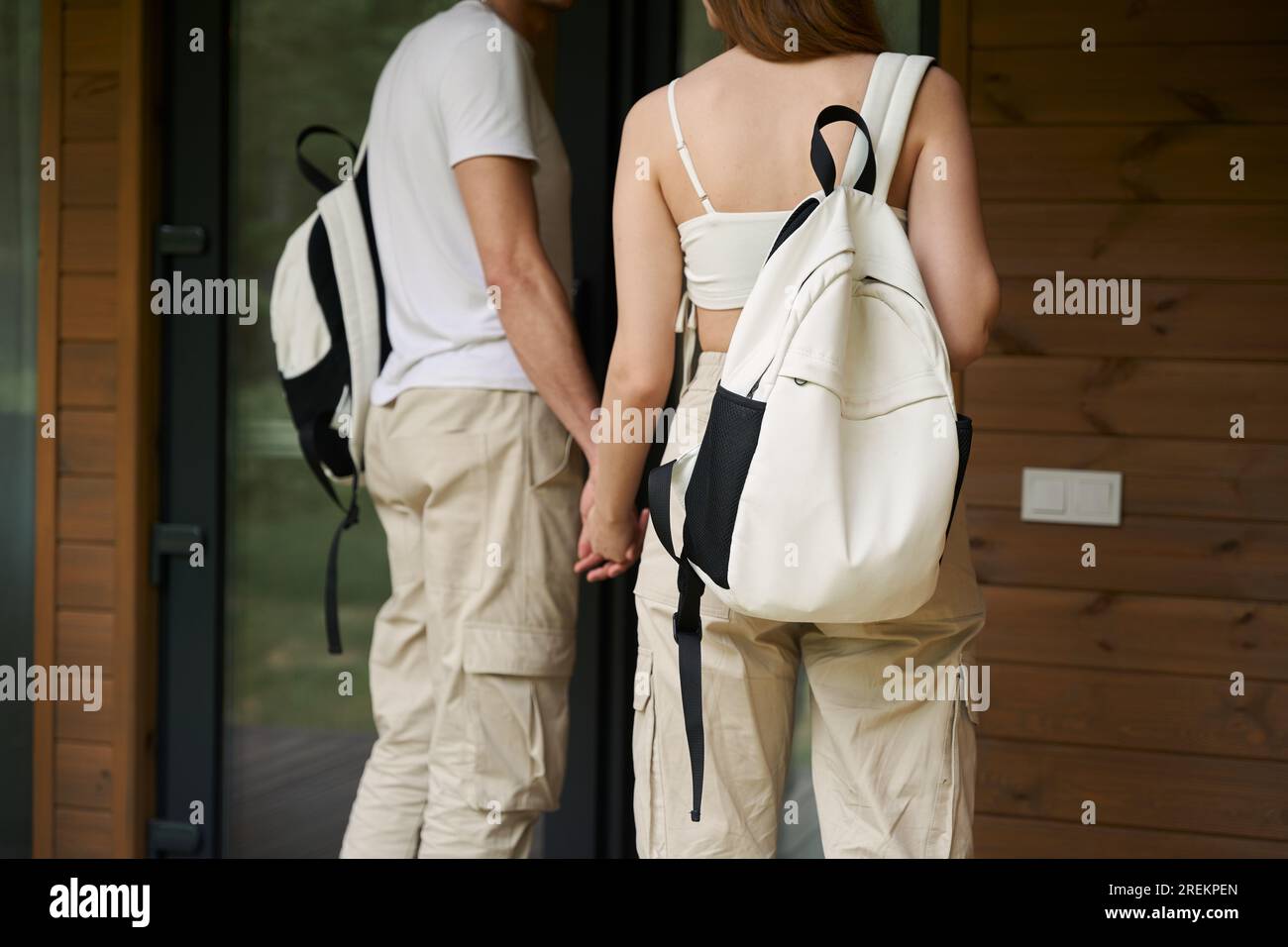 Back view of young man and a woman with backpacks holding hands Stock ...