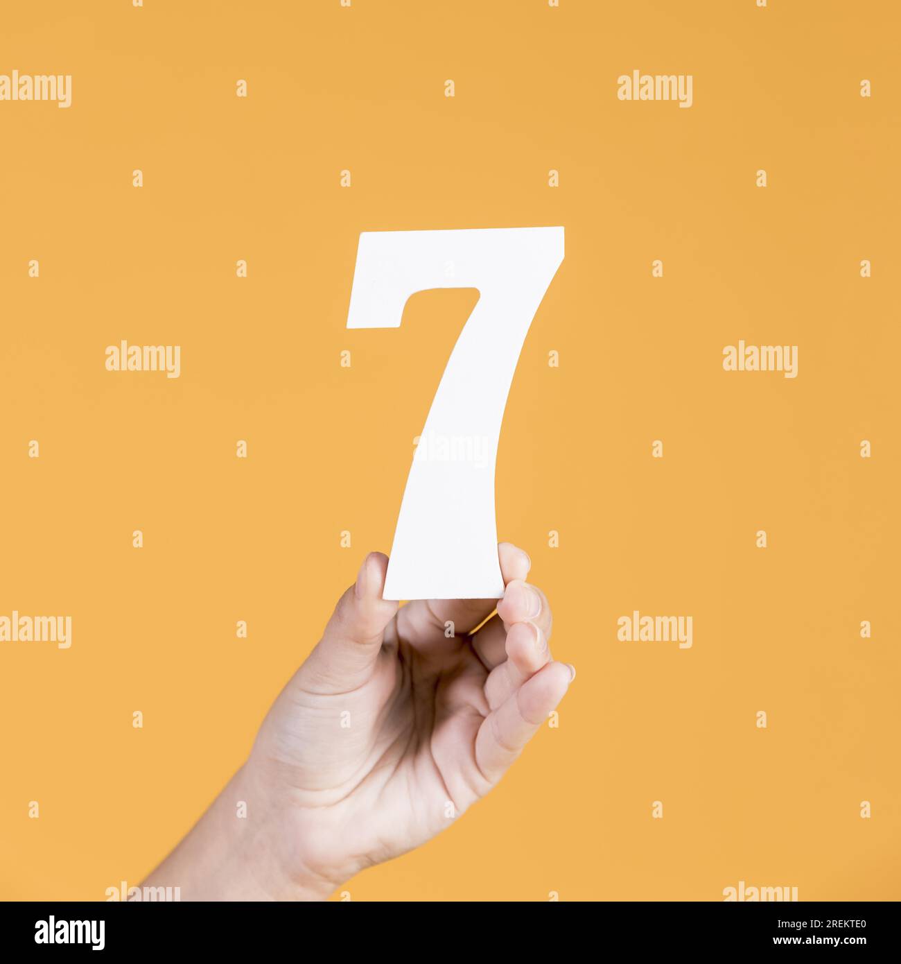 Human hand holding number seven against yellow background. Resolution ...