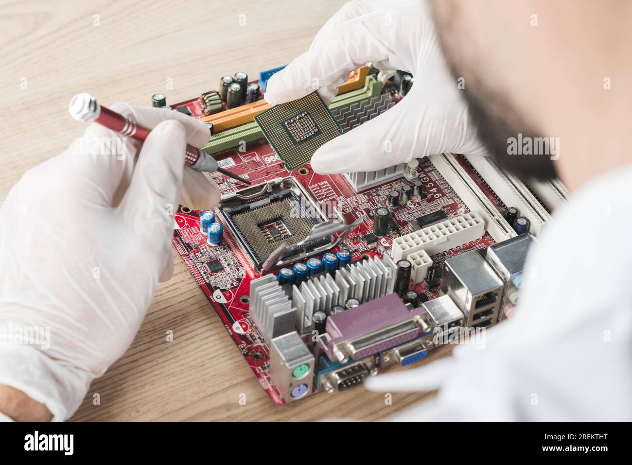Male technician inserting chip computer motherboard wooden desk ...