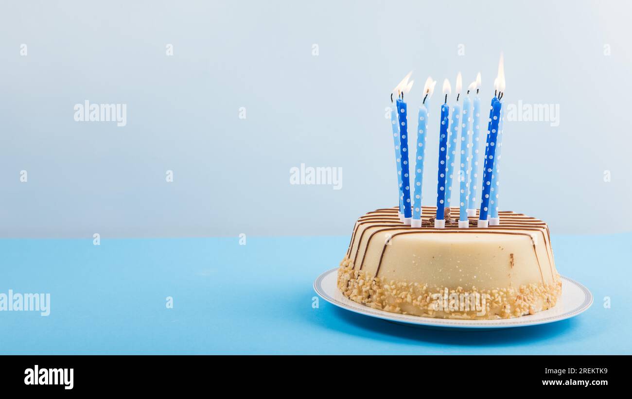 Lighted candles delicious cake against blue backdrop. Resolution and ...
