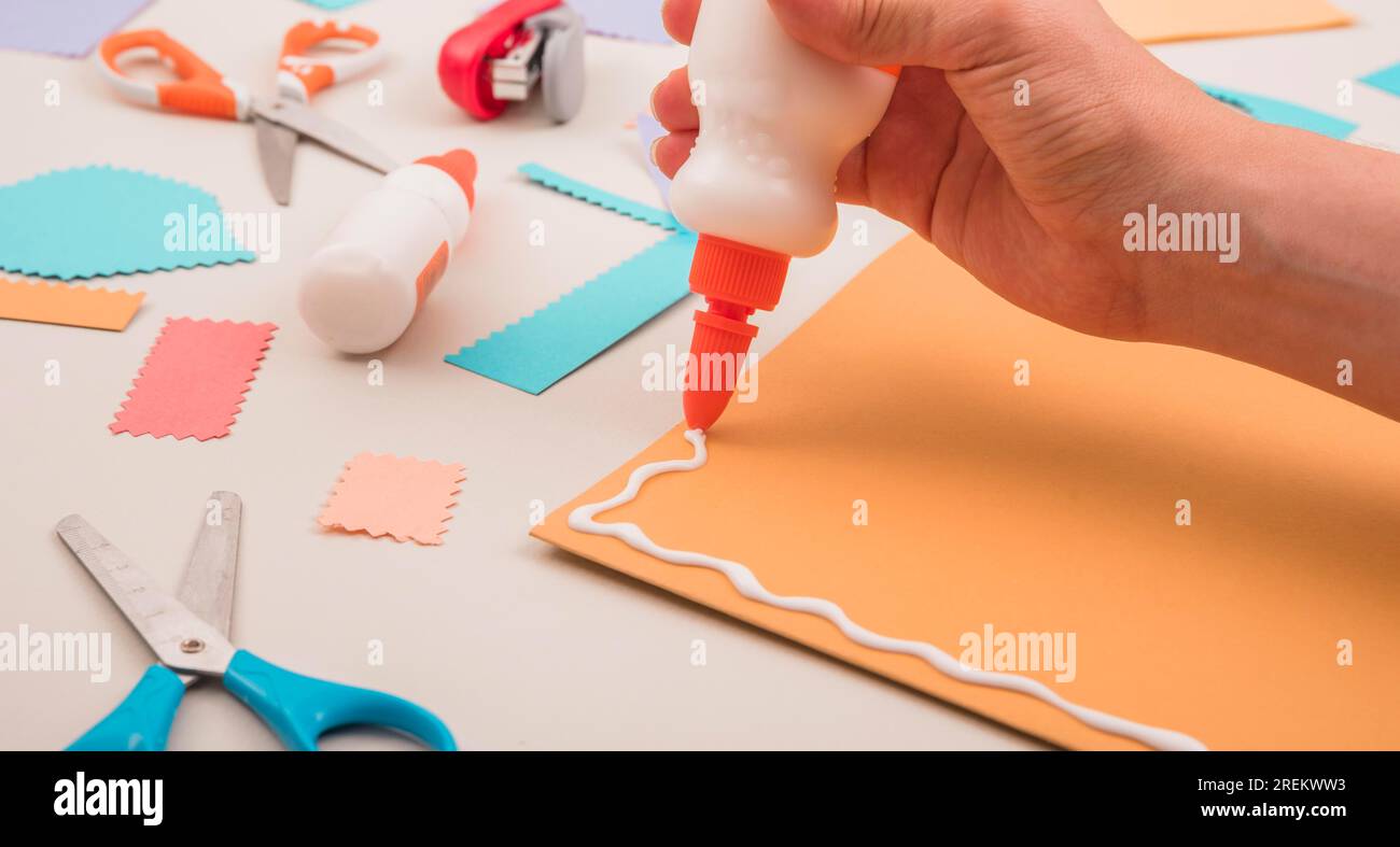 Human hand applying white glue orange paper with scissor stapler Stock ...