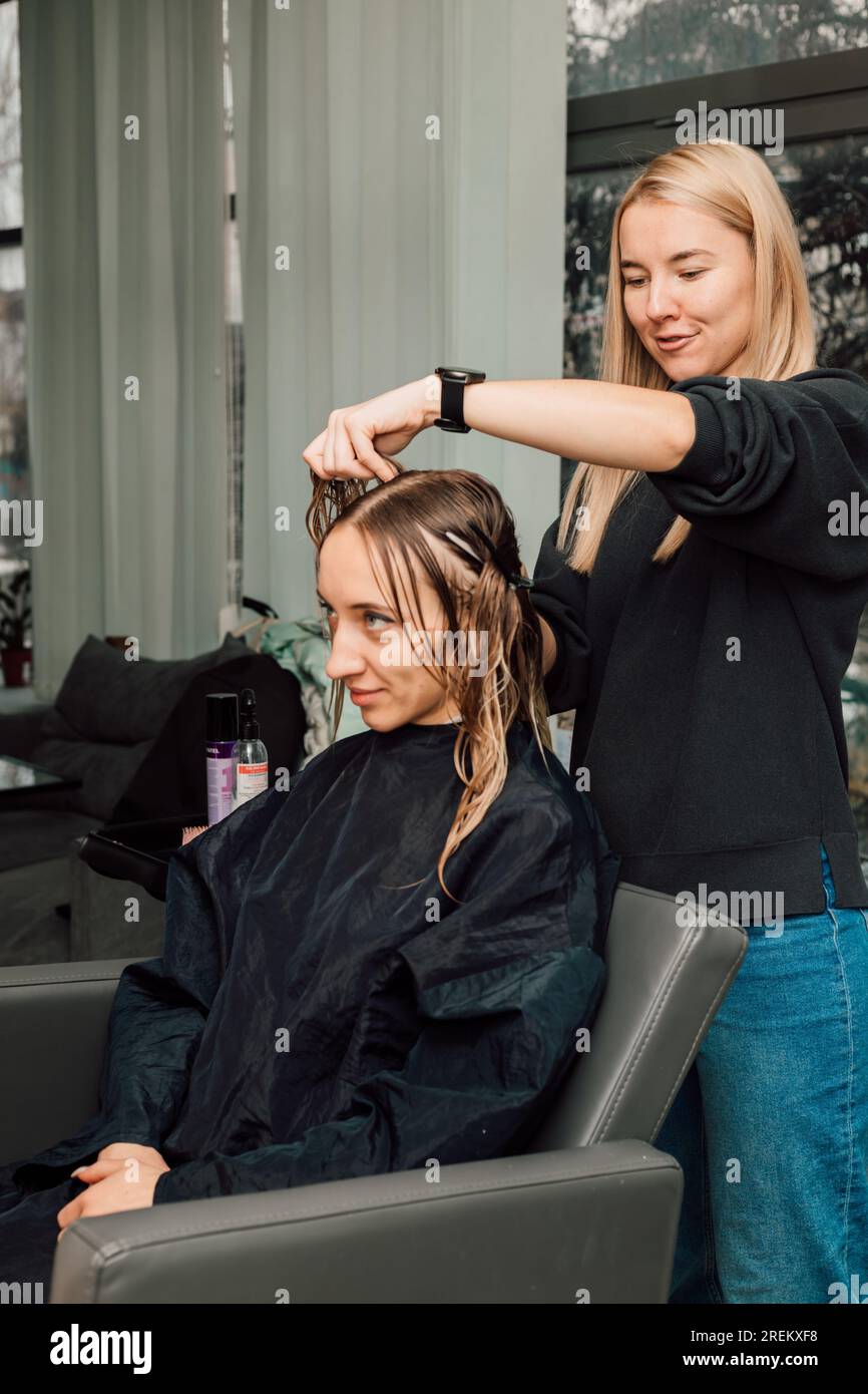 A hairdresser cuts a blonde's hair in a beauty salon. Women's haircut ...