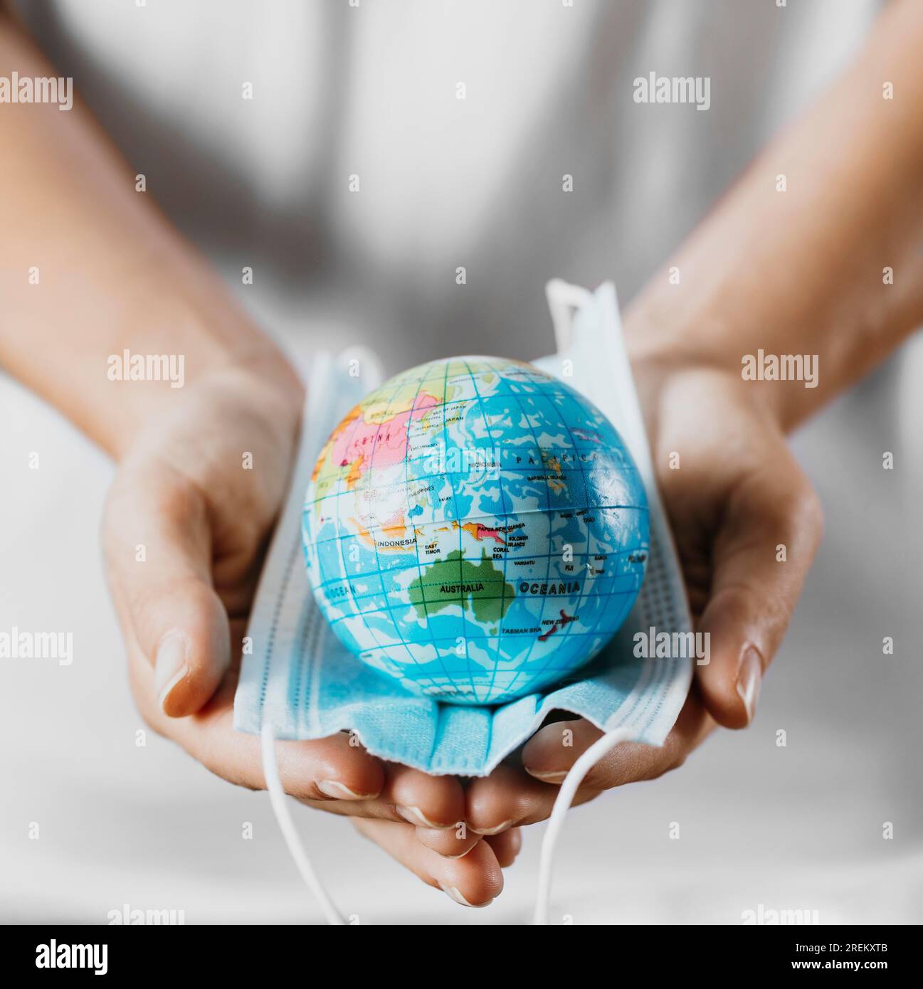 High angle person holding medical mask with earth globe. High ...