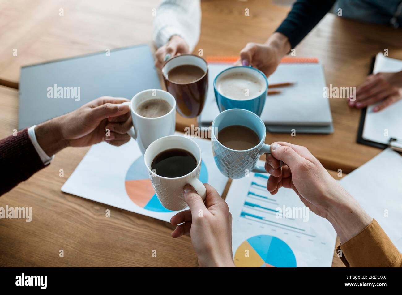 High angle people cheering with coffee mugs during office meeting. High ...