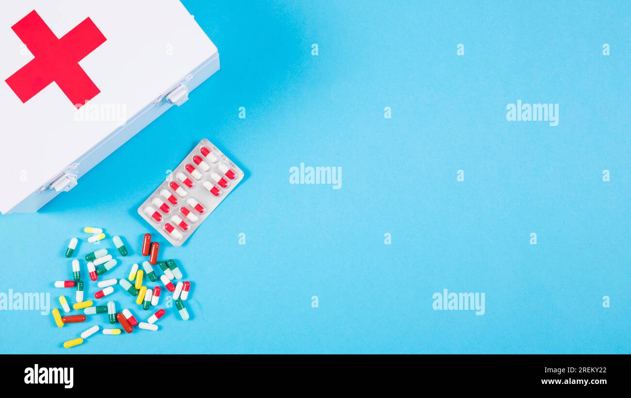 Overhead view first aid kit with colorful capsules blue background ...