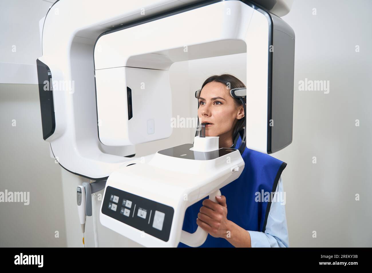 Brunette patient in protective apron is undergoing 3D scanning ...