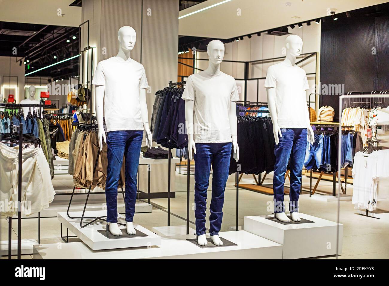 male mannequins in matching white t-shirts and jeans stand in a shop ...