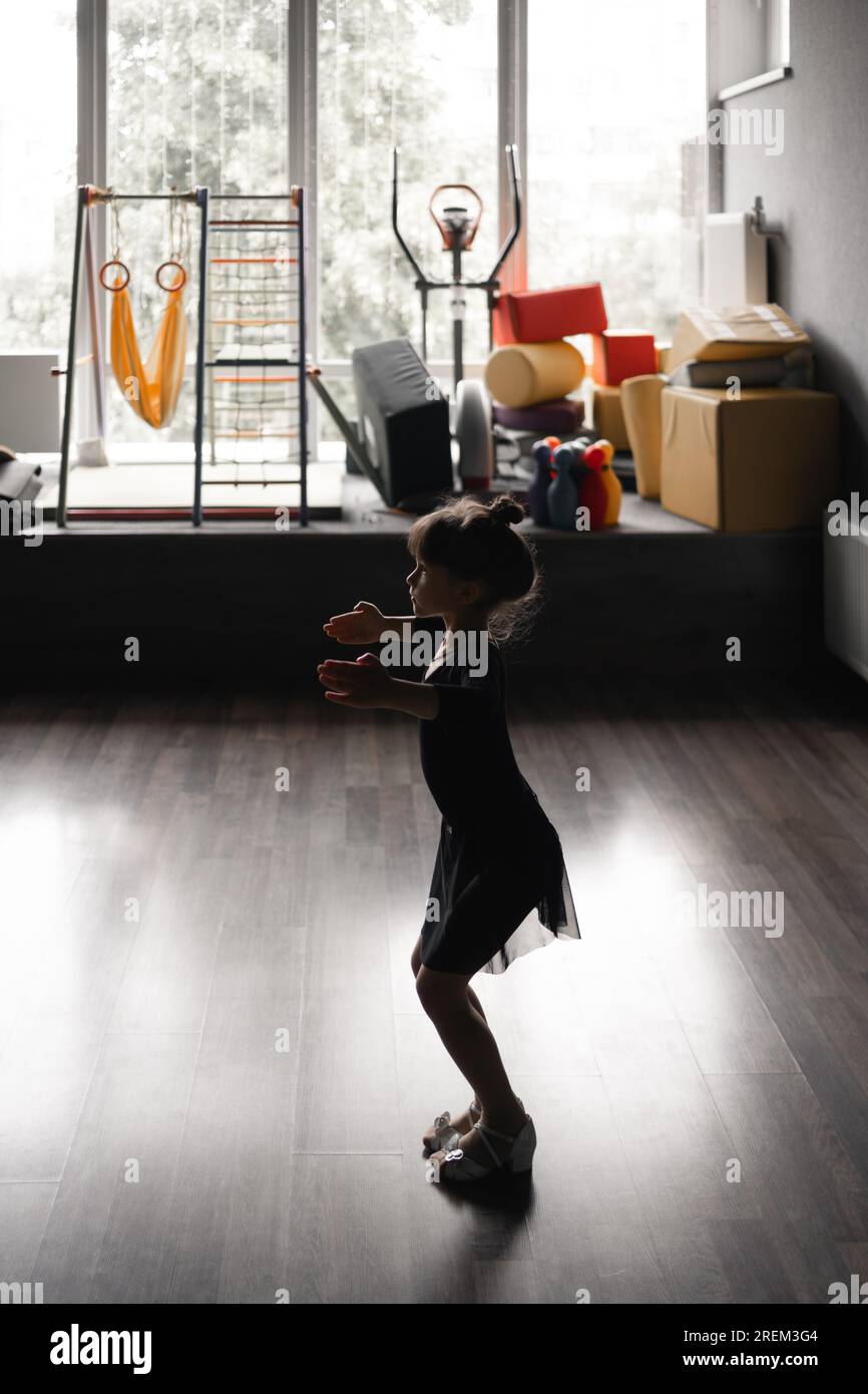 Child girl standing in black sport bodysuit in dancing studio during ...