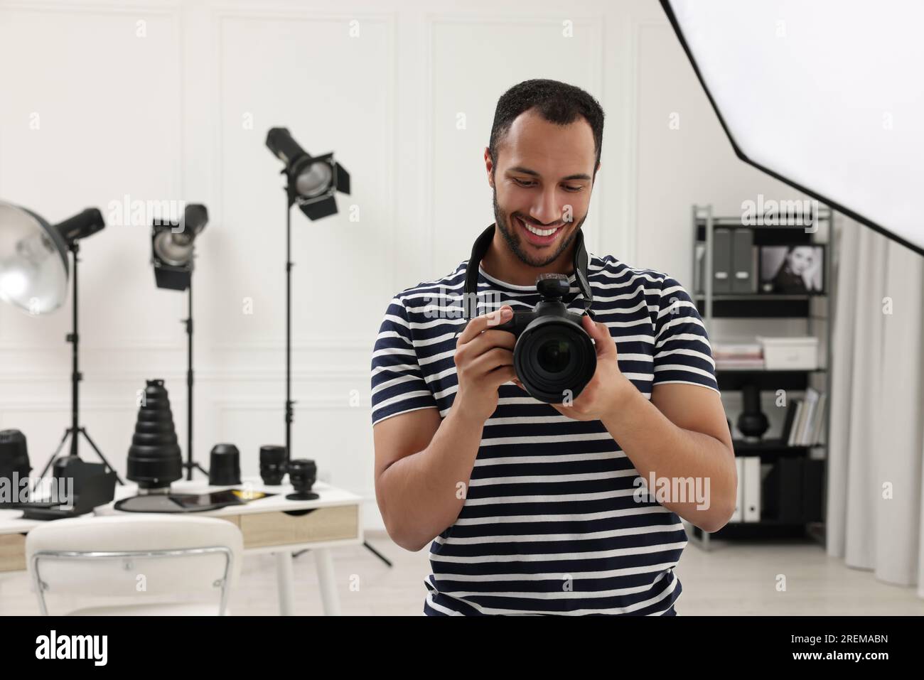 Young professional photographer with camera in modern photo studio ...