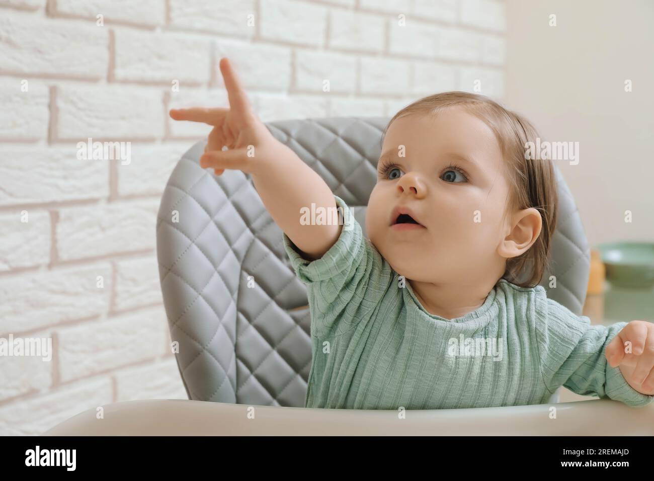Cute little baby pointing at something in high chair indoors Stock ...