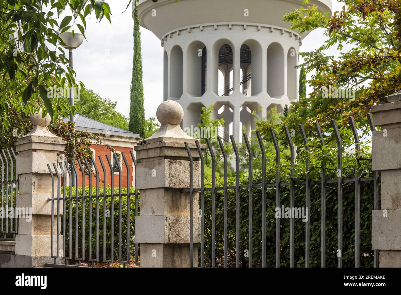 Metal and stone fence of an urban park with a large elevated water tank ...