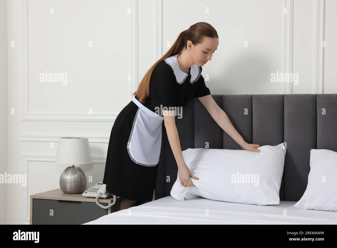 Young maid making bed in hotel room Stock Photo - Alamy