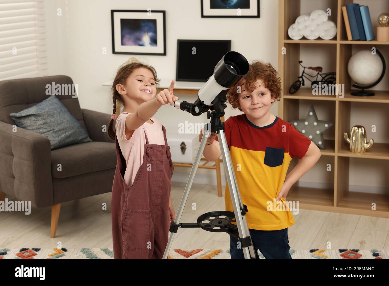 Cute little children using telescope to look at stars in room Stock ...