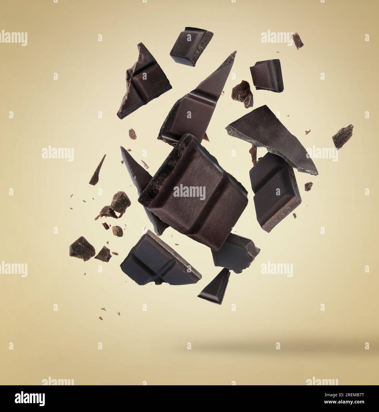 Broken chocolate bar pieces falling on beige background Stock Photo - Alamy