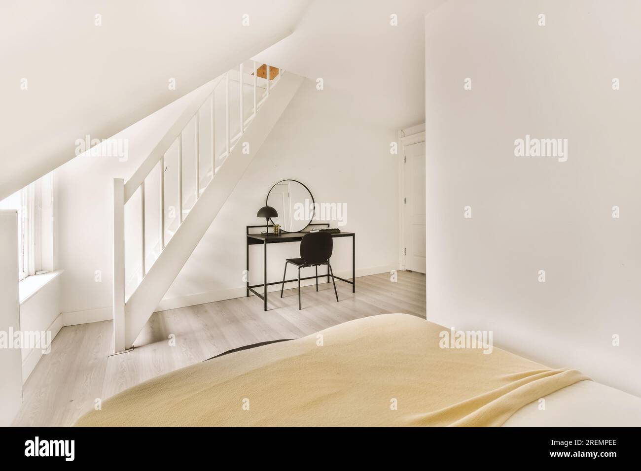 a bedroom with a bed, desk and stairs leading to the second floor in an ...