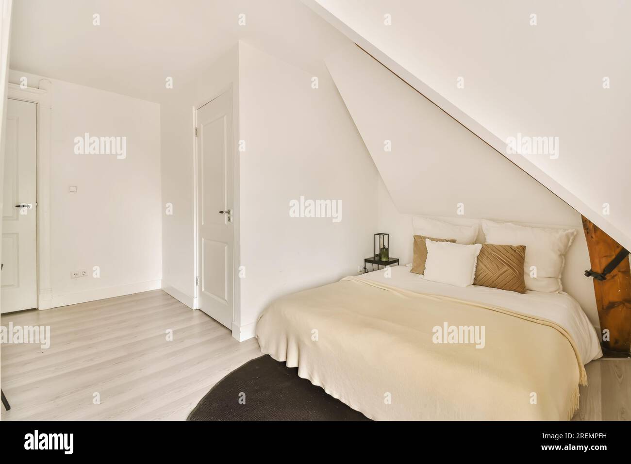 a bedroom with white walls and wood flooring in an attic - style home ...