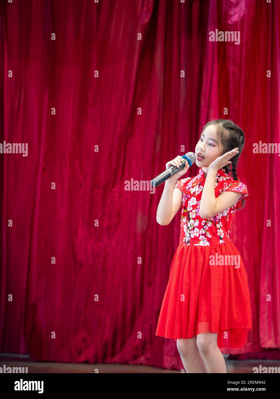 The Asian kid girl sing a song on stage at her school activity day ...