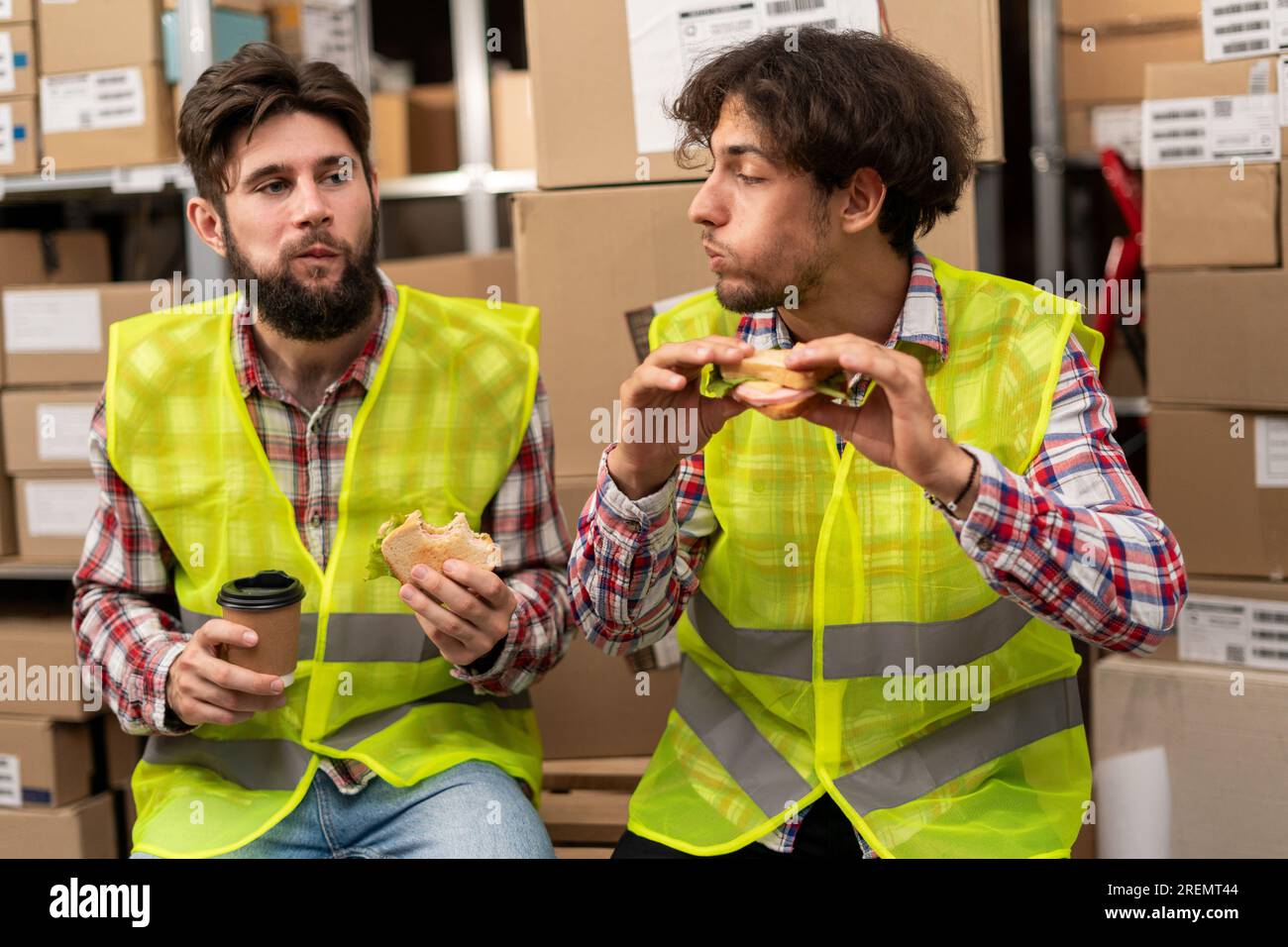 Time for a break. Two workers are eating sandwiches, drinking coffee ...
